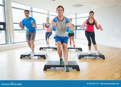 Instructor With Fitness Class Performing Step Aerobics Exercise With