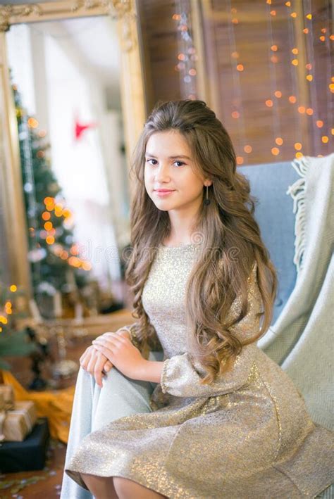 A Cute Teenage Girl With Long Curly Hair In A Shining Dress In A Room