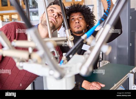 two engineers collaborating on programming a robotic arm for industrial