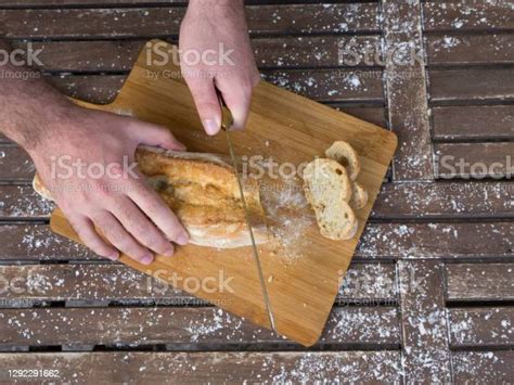통곡물 빵은 주방 장작 접시에 앉아 요리사가 금칼을 들고 잘라냅니다 테이블 클로즈업에 신선한 빵 부엌 테이블에 신선한 빵 건강 한 식사와 전통적인 빵집 가정 생활에 대한
