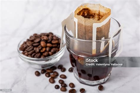 집에서 커피를 만드는 추세 갈색 배경에 커피 원두가 든 유리잔에 신선한 음료가 담긴 가방을 드립한다 컵에 양조하기위한 분쇄 커피