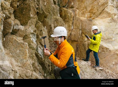 Male And Female Geologists Takes A Sample Of The Mineral And Record Data In A Canyon Stock Photo