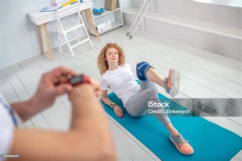 매트에 누워 여성 환자 그녀의 다리를 구부리고 남성 물리 치료사 손 스톱워치와 시간을 기록 X세대에 대한 스톡 사진 및 기타 이미지 Istock