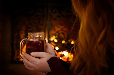 긴 머리를 가진 어린 소녀가 벽난로 앞에 앉아 차 한 잔을 들고 몸을 따뜻하게 합니다 따뜻함 꿈 행복의 개념 클로즈업 선택적 초점 열 개념에 대한 스톡 사진 및 기타 이미지