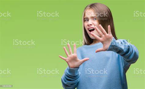 젊은 아름 다운 소녀 두려워 하 고 손으로 공포 식 정지 동작으로 겁에 질 려 고립 된 배경 위에 겨울 스웨터를 입고 충격에서 소리 공황 개념입니다 가을에 대한 스톡 사진