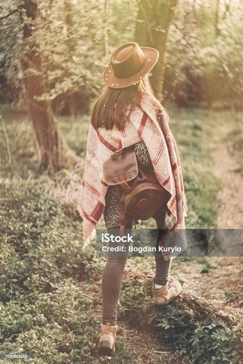 방 랑 벽 개념입니다 저녁 햇살에 숲에서 걷는 배낭 모자에 세련 된 Hipster 소녀 여자 여행자 다시 햇빛이 나무 들 사이 볼 텍스트를 위한 공간입니다 대기 순간 가을에