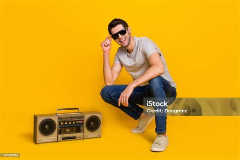 붐박스 근처에 앉아있는 멋진 브루넷 젊은 남자의 풀 사이즈 사진 노란색 배경에 고립 된 티셔츠 안경 청바지 운동화를 착용하십시오 25 29세에 대한 스톡 사진 및 기타