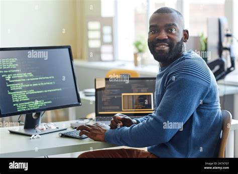 Portrait Of Black Man As Computer Programmer Looking At Camera While
