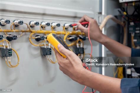 Engineer Testing Electrical System Using A Multimeter To Measure The Current At The Control