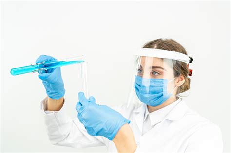 과학 화학 실험실에서 파이펫을 사용하여 테스트 튜브에 파란색 액체 물질을 떨어 뜨리는 보호 안경 마스크 및 장갑을 착용한 젊은 매력적인 농축 여성 과학자 20 24세에 대한