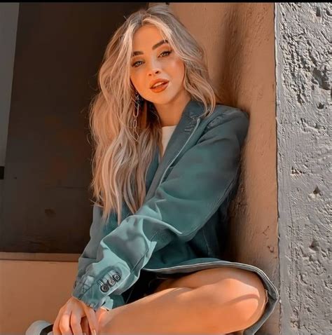 A Woman Sitting On The Side Of A Building With Her Legs Crossed And