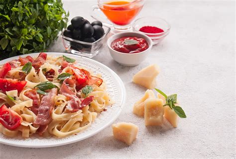 베이컨 계란 파마산 치즈와 바 질이 있는 클래식 한 파스타는 밝은 배경입니다 테이블 옆에는 파마산 치즈 향신료 올리브 토마토 소스가 있습니다 복사 공간 강판에 대한 스톡