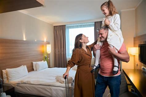 Mother Caressing Joyful Daughter On Father S Shoulders In Hotel Room