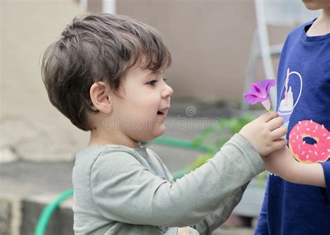 Brother And Babe Playing With A Purple Flower In The Backyard Stock Photo Image Of Domestic