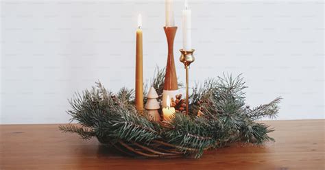 스웨덴 종이 별이 있는 흰 벽을 배경으로 나무 테이블에 촛불과 장식이 있는 세련된 크리스마스 화환 대기 겨울 시간 휴일 강림절 스칸디나비아 축제 휘게 사진