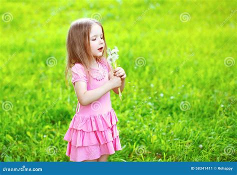 Милый ребенок маленькой девочки в цветке одуванчика платья дуя Стоковое Изображение