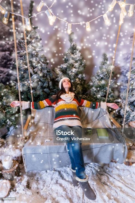눈이 하는 동안 니트 모자와 스카프를 착용 하는 눈 덮인 공원에서 손전등 아래 스윙에 뻗은 팔을 아래로 쾌활 한 젊은 여 자가 거짓말 12월 31일에 대한 스톡 사진 및
