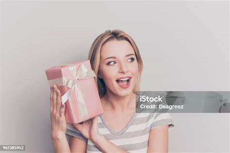 예쁜 매력적인 달콤한 세련 된 호기심 소녀 하얀 나비 포장 분홍색 상자가 현재 오픈 입으로 귀 근처 회색 배경에 고립 무엇을 알고 하려고의 초상화 여자에 대한 스톡 사진 및