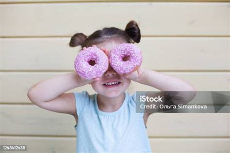 두 개의 분홍색 도넛 평범한 나무 배경을 통해 찾고 어린 소녀의 초상화 2015년에 대한 스톡 사진 및 기타 이미지 2015