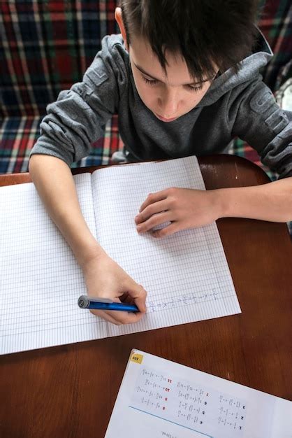 Premium Photo Boy Writing In Book While Sitting On Table