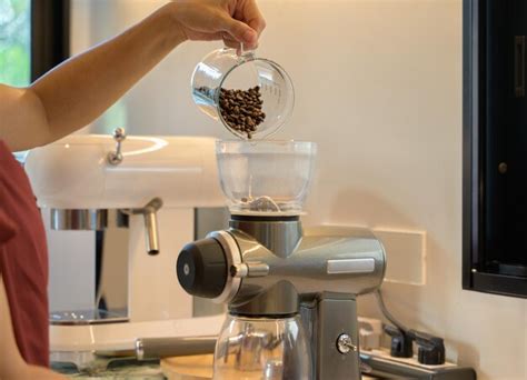 Woman Pouring Coffee Beans Into The Coffee Grinder Machine In The Kitchen At Homexa Premium Photo