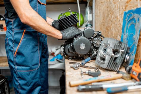 작업장의 작업 테이블에서 수리하는 동안 오토바이 엔진을 분해하는 작업자 얼굴 없이 클로즈업 사진 Unsplash의