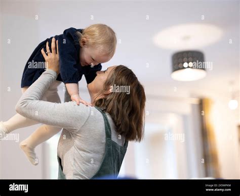 Mother Lifting Daughter At Home Stock Photo Alamy