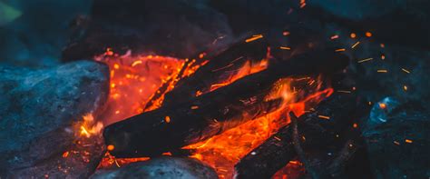 불에 타버린 생생한 연기가 나는 장작이 클로즈업되었습니다 모닥불의 주황색 불꽃이 있는 분위기 있는 배경 모닥불의 상상할 수없는 풀 프레임 이미지 공중에서 빛나는 불씨 따뜻한