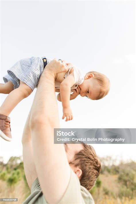 플로리다 주 주피터 농장 의 공원에서 노란 야생화와 마른 풀밭에서 쿠바 계 미국인 아기 아들을 안고있는 31 세의 미국인 아버지 아이에 대한 스톡 사진 및 기타 이미지