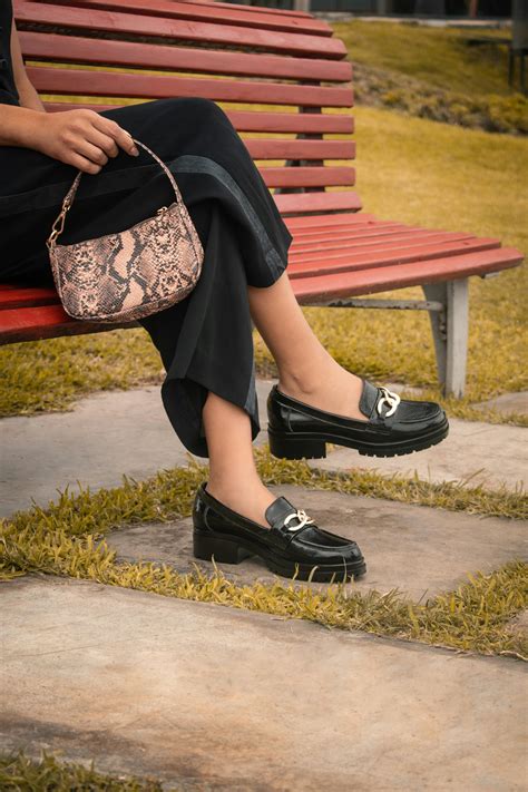 검은 구두 검은색 에나멜 가죽 고전적인 스타일 교차 다리 기발한 녹색 의자 다리를 건너다 무늬 카펫 발목 발목에서 교차된 다리 부드러운 조명 빈티지