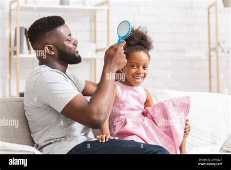 Loving black father brushing his cute daughter hair Stock Photo - Alamy