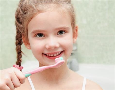 دختر کوچک ناز خندان در حال مسواک زدن در مفهوم بهداشت حمام 1640190