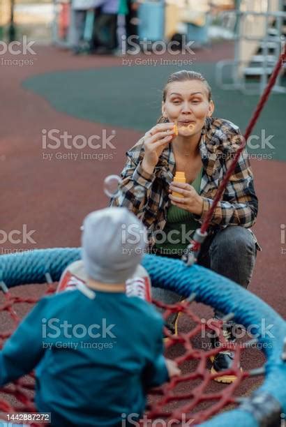 재미있는 모자를 쓴 다운 증후군을 가진 귀여운 어린 소년이 어머니와 함께 놀이터에서 회전목마를 돌고 있다 2명에 대한 스톡 사진 및 기타 이미지 Istock