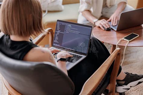 Back View Of Young Woman Programmer Writes Program Code On Laptop While Sitting In Modern