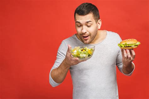 샐러드와 햄버거 건강 하 고 정크 음식 사이 선택 생각 하는 남자 다이어트 개념입니다 좋은 건강 하 고 나쁜 유해한 음식 사이 선택 유기농 식품 대 패스트 푸드 빨간색 절연
