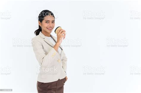 카메라를 보면 하얀 배경에 고립된 커피나 차 한 잔을 들고 포즈를 취하는 젊은 사업가의 모습이 그려진다 성취 경력 재산 사업 개념 개념에 대한 스톡 사진 및 기타 이미지