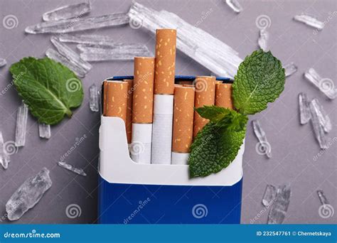Pack Of Cigarettes Menthol Crystals And Mint Leaves On Grey Background