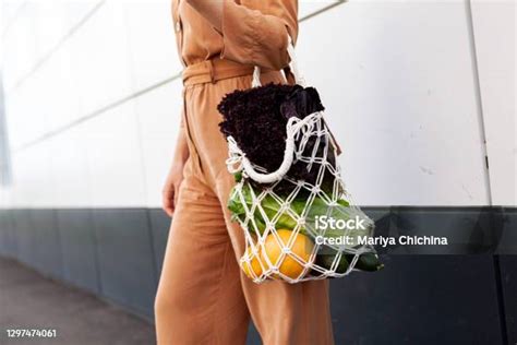 소녀는 비닐 봉지없이 야채 채소와 메쉬 쇼핑 백을 들고있다 제로 폐기물 플라스틱 무료 환경 친화적 인 개념 수제 마크라메 백 지속 가능한 라이프 스타일 가방에 대한 스톡