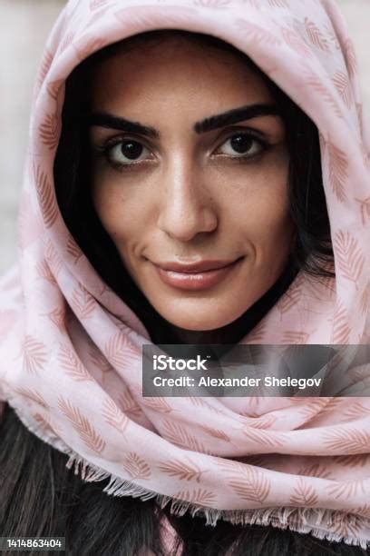 히잡처럼 분홍색 머리 스카프를 입은 아름다운 무슬림 여성의 여성 초상화 좋은 동양 사람들의 라이프 스타일 사진 소녀는 어두운 피부와 갈색 눈을 가진 갈색 머리입니다 아랍어