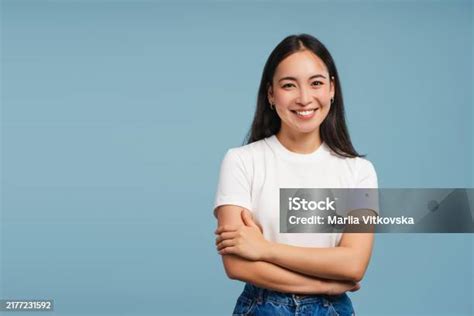 팔짱을 끼고 포즈를 취하는 웃는 아시아 여성이 파란색 배경에 카메라를 보고 있습니다 여자에 대한 스톡 사진 및 기타 이미지 여자 미소 인물 사진 Istock