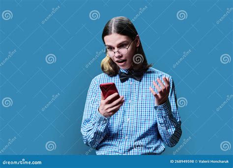 Jovencito Sorprendido Alegre Mirando En Un Smartphone Con Fondo Azul Foto De Archivo Imagen De