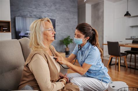 고위 여성 옆에 앉아 코로나 발병 중에 폐를 확인하기 위해 청진기를 사용하는 보호 마스크를 가진 간호사 폐에 대한 스톡 사진 및 기타 이미지 Istock