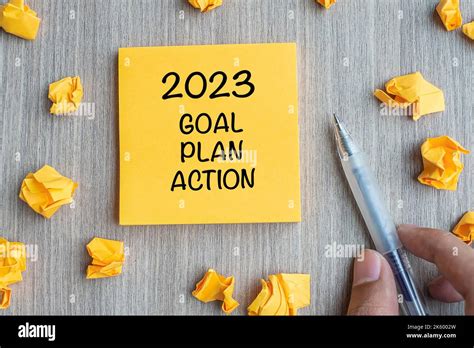 2023 goal plan action word on yellow note with businessman holding pen and crumbled paper on