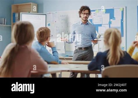 Elementary School Physics Teacher Uses Interactive Digital Tablet To Show To A Classroom Of
