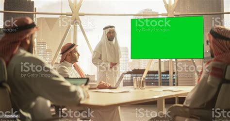 아랍 사업가가 사우디 투자자 그룹에 데이터를 보여줍니다 그린 스크린 모의 디스플레이가 있는 tv 화면 현대 사무실의 회의실에서
