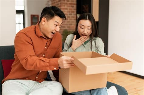 Premium Photo Surprised Asian Man And Woman Looking Inside Cardboard