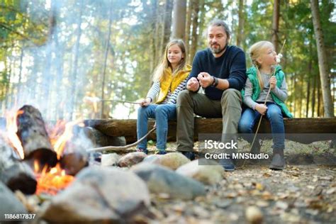 귀여운 여동생과 그들의 아버지는 모닥불에 막대기에 마시멜로를 구이 캠프 파이어에서 재미를 아이들 가을 숲에서 아이들과 캠핑 먹기에 대한 스톡 사진 및 기타 이미지 Istock