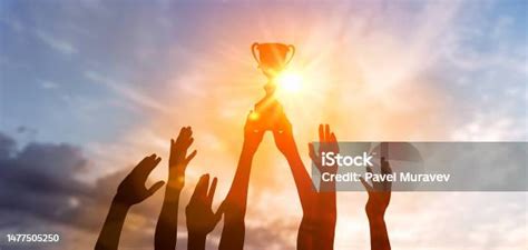 실루엣 비즈니스 팀이 수상 트로피를 들고 승리 비즈니스 성공 일몰 배경을 보여줍니다 하늘에서 빛나는 태양을 상대로 트로피 컵을