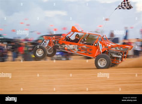 Orange Sand Car Racing While On The Back Wheels In The Sand Dunes Stock