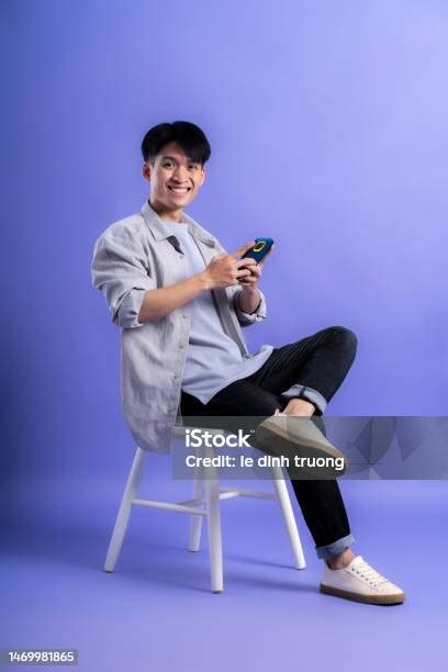 보라색 배경에 전화를 사용하는 젊은 아시아 남자의 전신 이미지 앉음에 대한 스톡 사진 및 기타 이미지 앉음 남자 의자 Istock